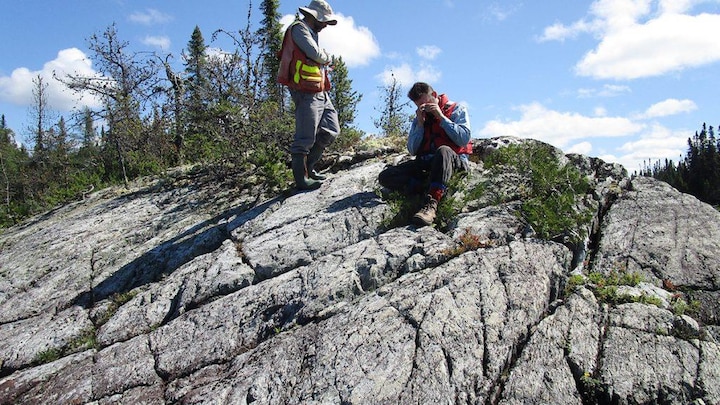 Deux personnes sur une roche l'observent.